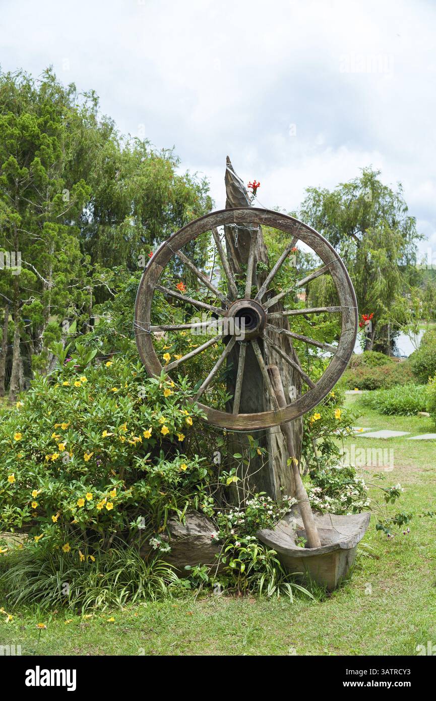 Garden design - old wooden wheel and mortar Stock Photo - Alamy