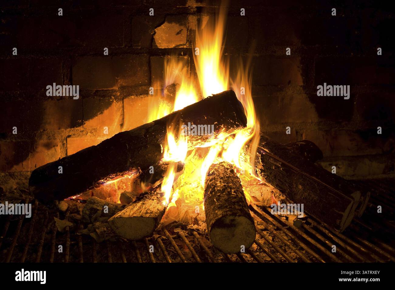Burning round logs in fireplace against brick smoked wall Stock Photo ...