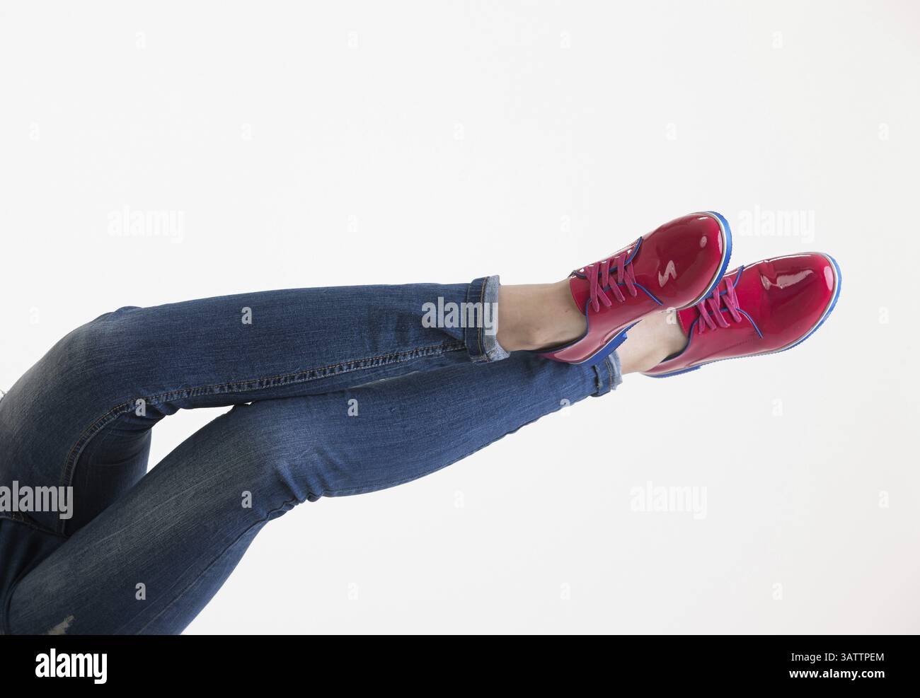 Woman's legs in blue jeans and red shoes isoltaed studio background ...