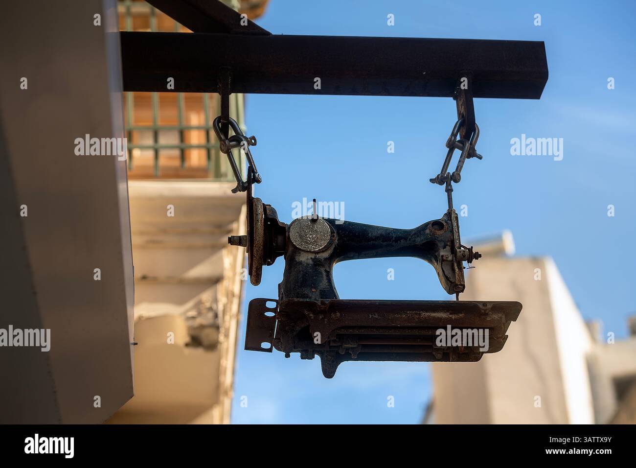Old vintage sewing machine hanging on a metal frame at the entrance of ...