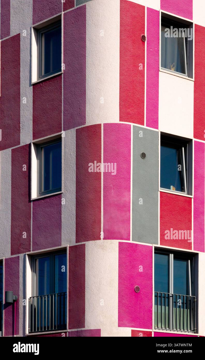 Modern residential building featuring a vibrant facade of pink, purple ...