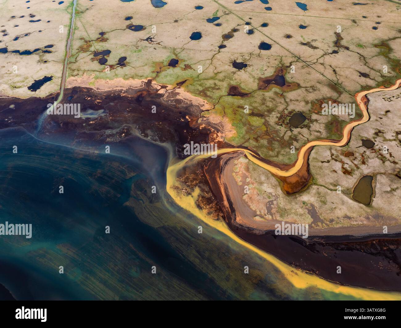Drone view of a vivid estuary where a yellow river merges into dark ...
