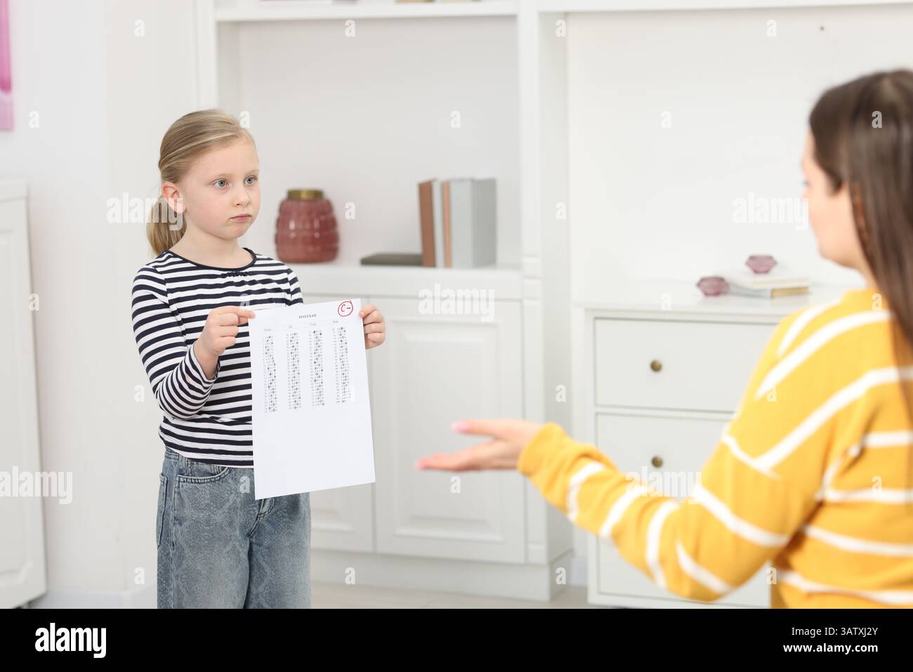 School grade. Sad girl showing answer sheet with bad mark to her mother ...
