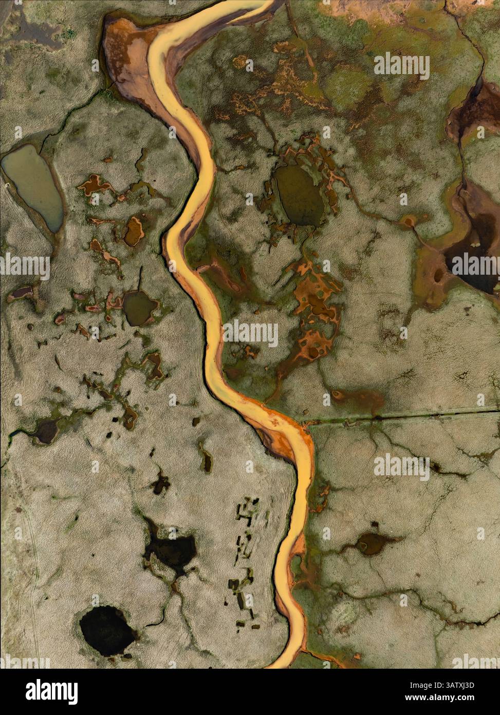 Vertical aerial of a winding yellow river surrounded by textured ...