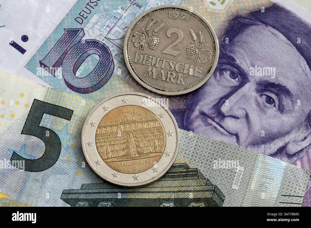 Geldscheine in Form von 10 Deutsche Mark oben und 5 Euro sowie Münzen ...