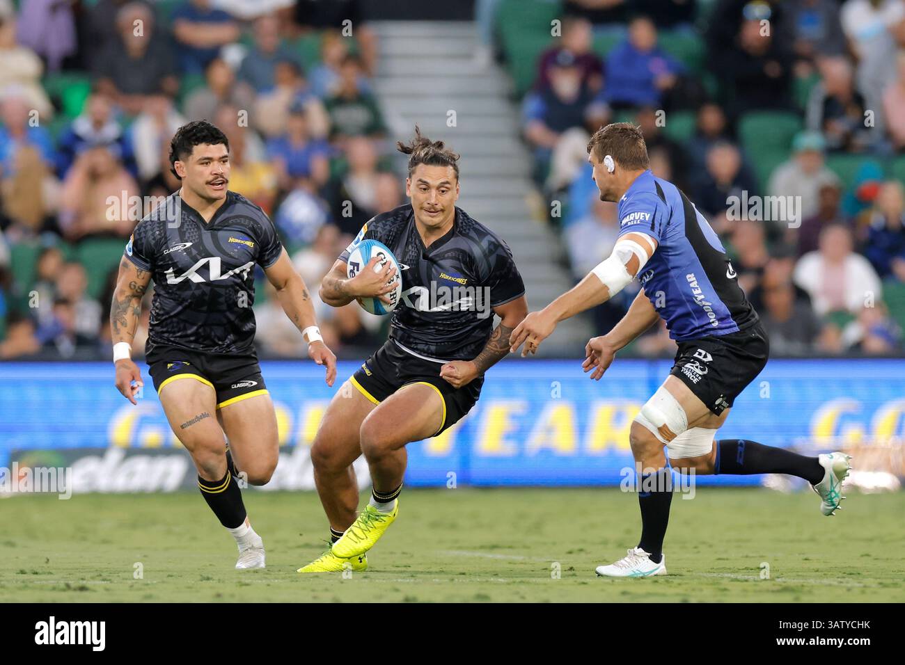 Peter Umaga-Jensen of the Hurricanes is tackled by Nick Champion de ...