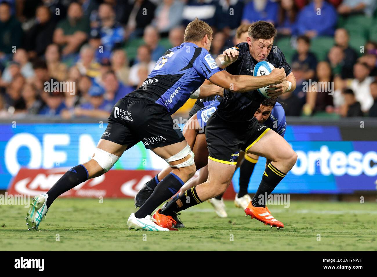 Cam Roigard of the Hurricanes is tackled by Nick Champion de Crespigny ...