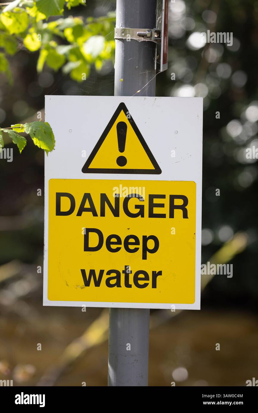 Close up of a yellow, black and white warning sign. Danger deep water ...