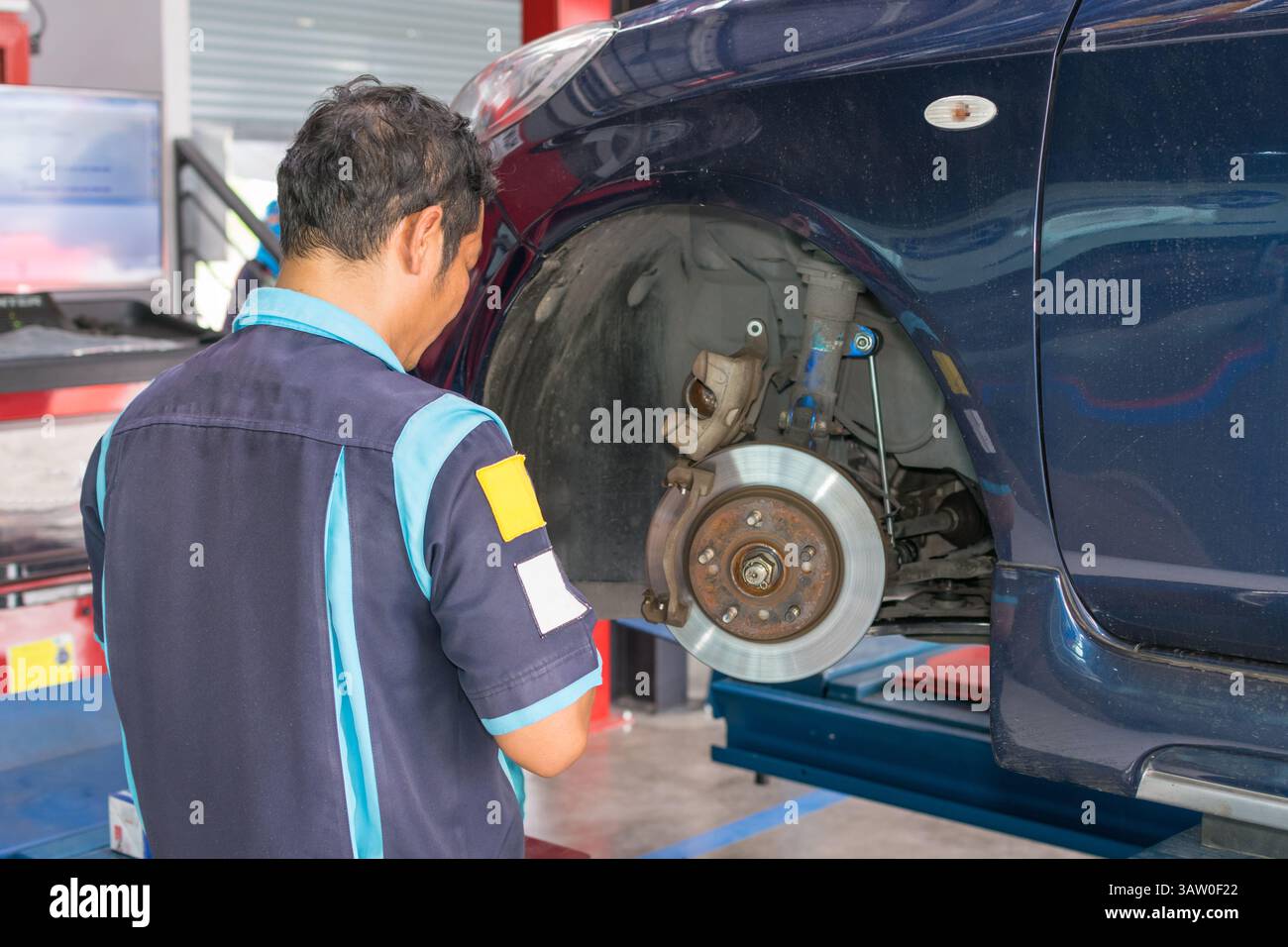Serviceman checking brake system in a car at garage Stock Photo - Alamy