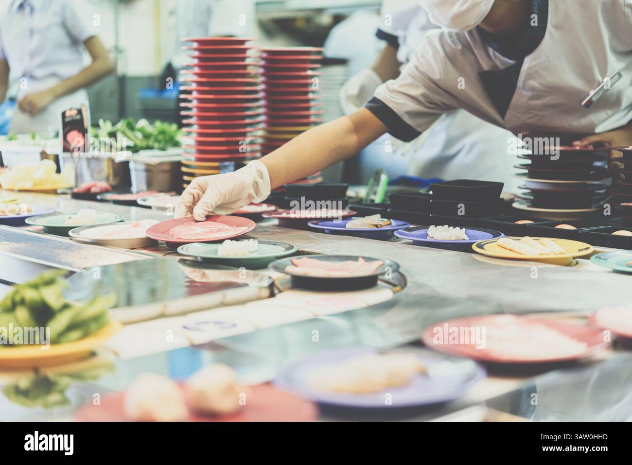 Chef cooking a food in the Japan food restaurant sushi conveyor or belt ...