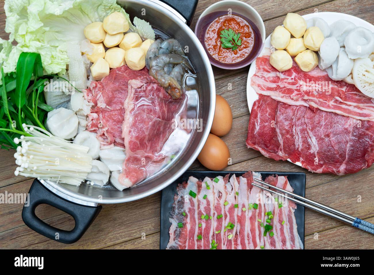 Cooking food by put a flesh beef, pork, egg and vegetable in to a hot ...