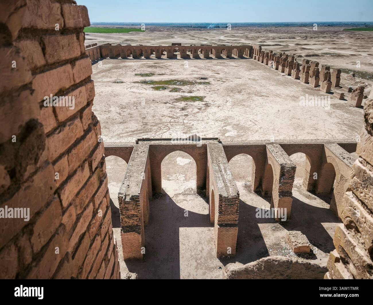 Ancient ruins of a large rectangular courtyard with arched doorways and ...