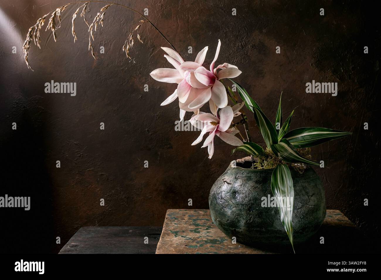 Beautiful pink magnolia flowers ikebana in rustic green ceramic vase ...