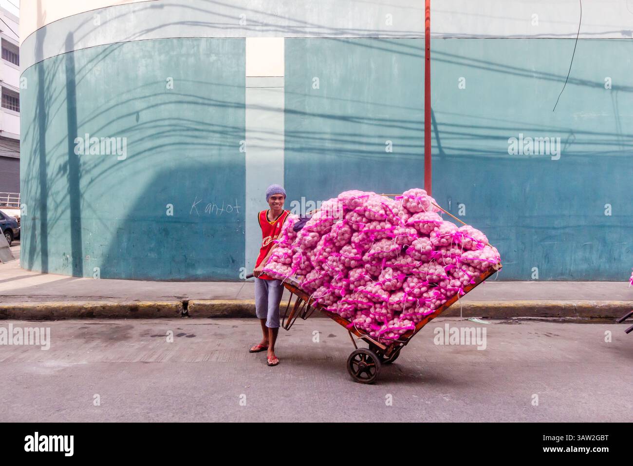 A Filipino laborer transports several sacks full of garlic through the ...