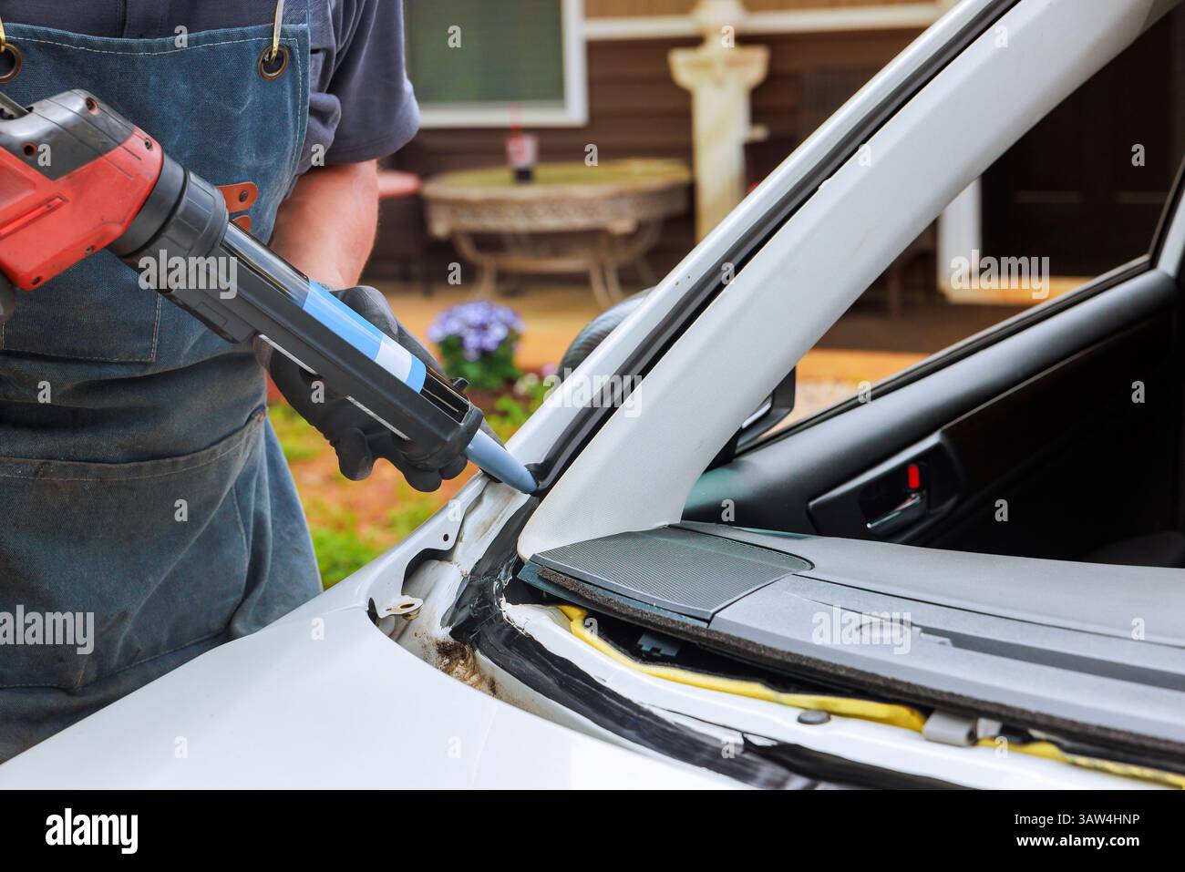 Technician works vehicle trim using caulking gun to seal windshield on ...