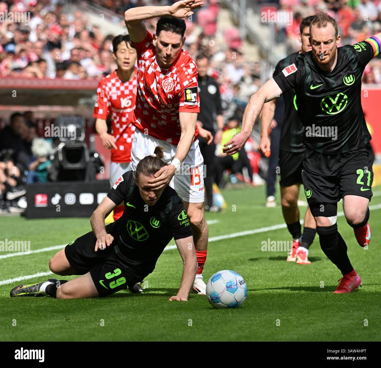 Mainz's Anthony Caci plays against Wolfsburg's Patrick Wimmer, below ...