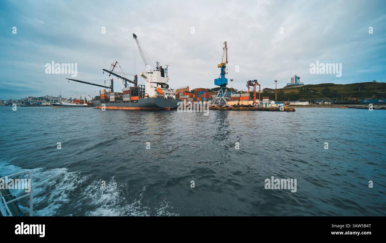 Massive cargo vessel approaching industrial harbor, loading containers ...