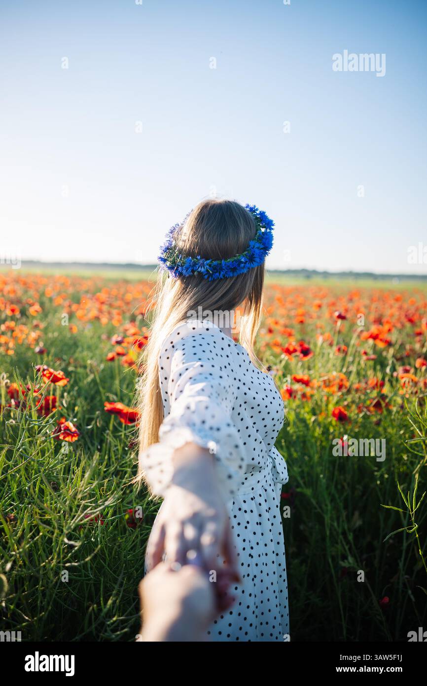 Romantic couple holding hands while walking through a vibrant poppy ...