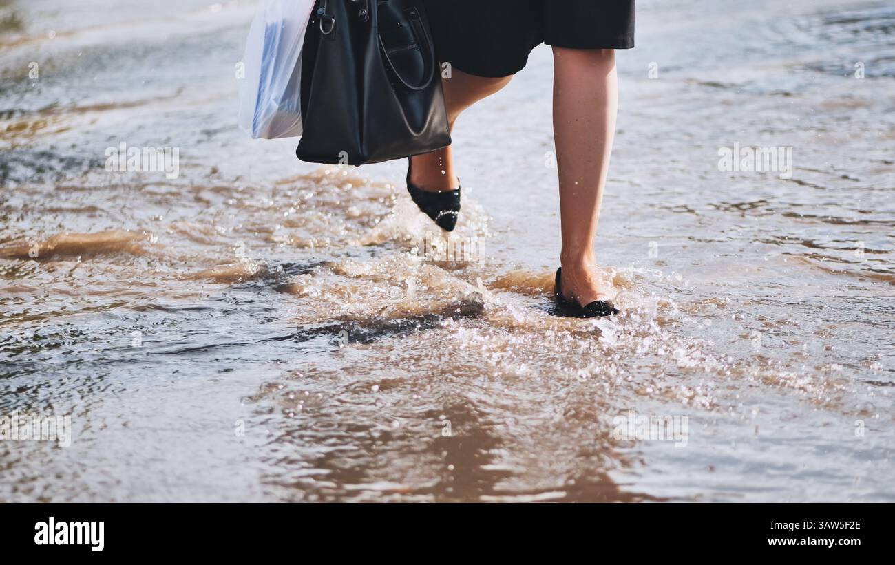 Businesswoman with handbag wading through a flooded street after heavy ...