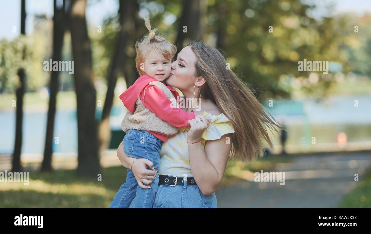 Loving mother tenderly kissing smiling daughter, embracing child during ...