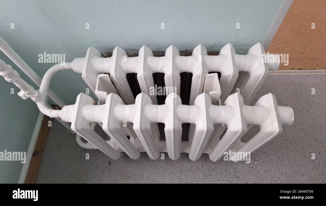 Antique white cast iron radiator in corner on gray floor Stock Photo ...