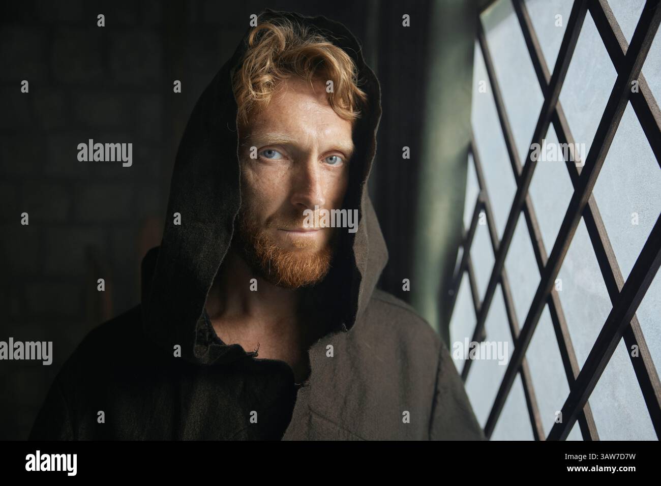 Portrait of pensive monk in medieval costume with hood looking through ...