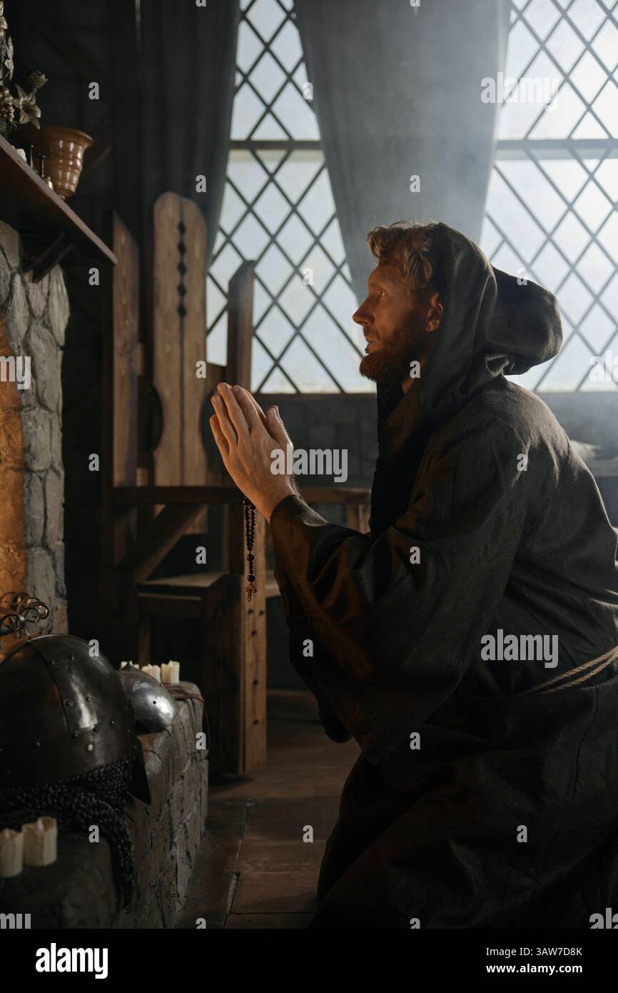 Solitary desperate priest kneeling before church altar in mystical ...