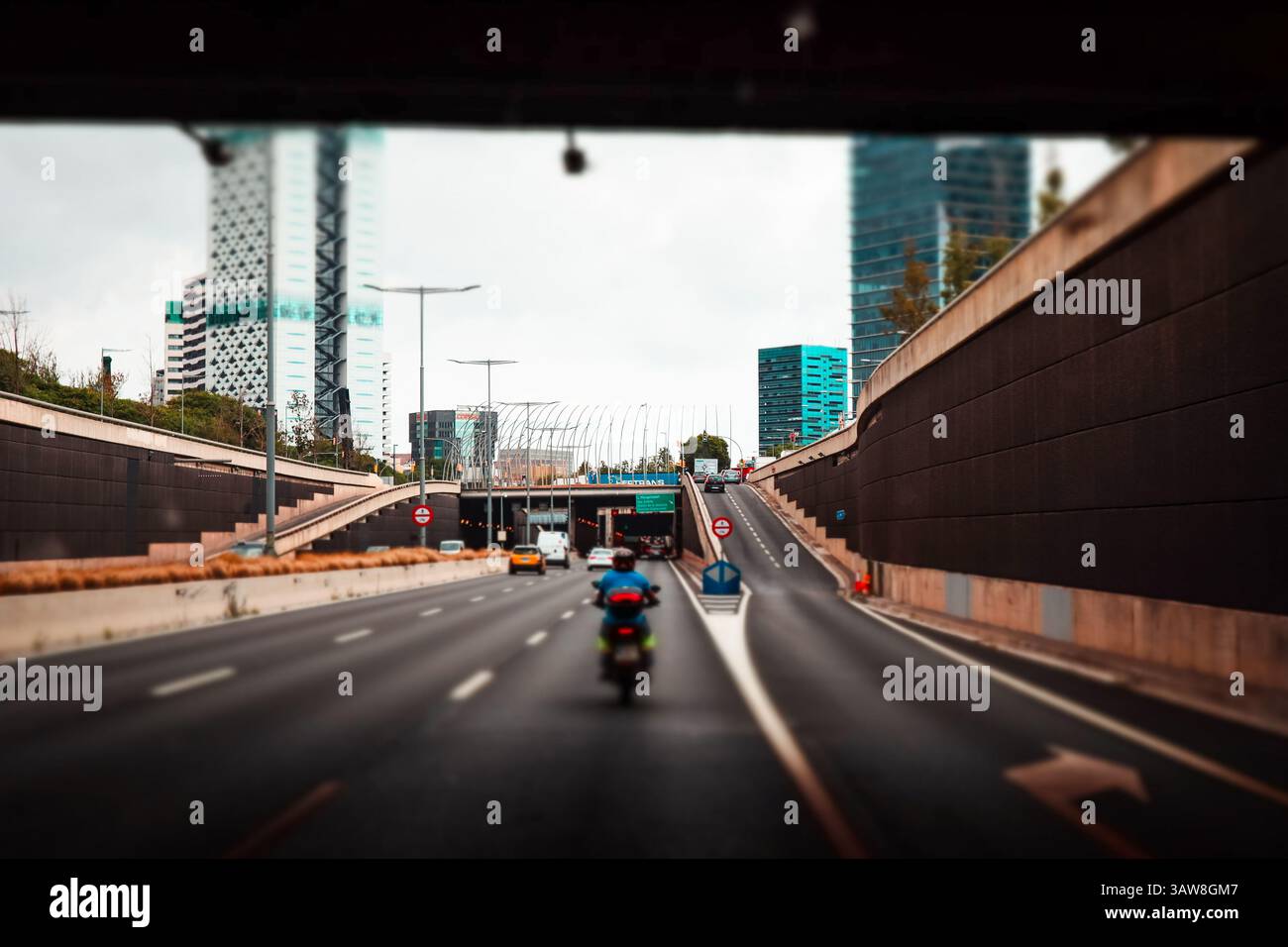 Vehicles drive through a tunnel on a multi-lane highway, buildings ...