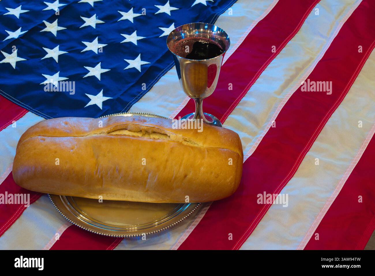A communion chalice with wine and a loaf of bread sit on top of an ...