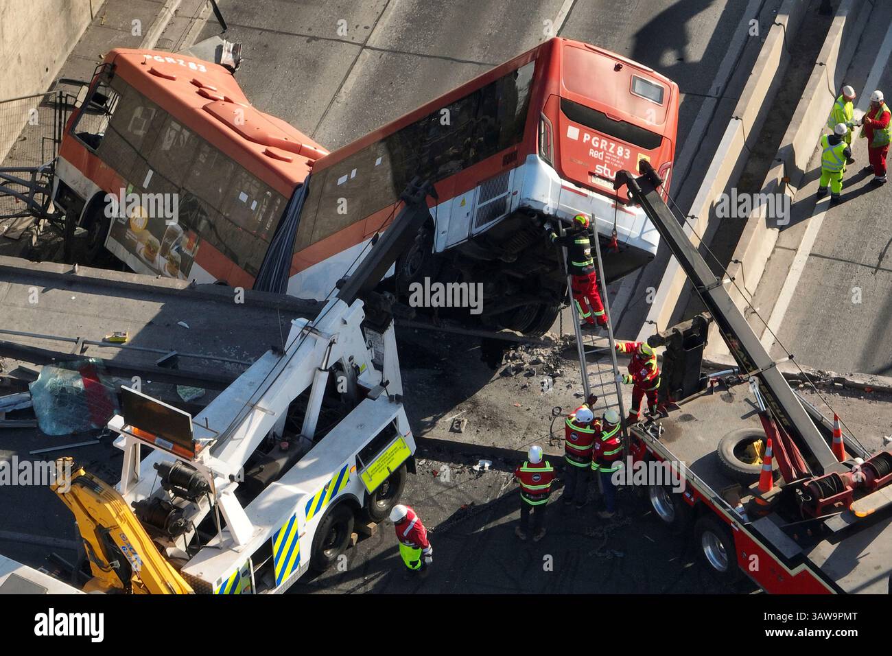 Firefighters work to remove a bus hanging off an overpass, after it ...