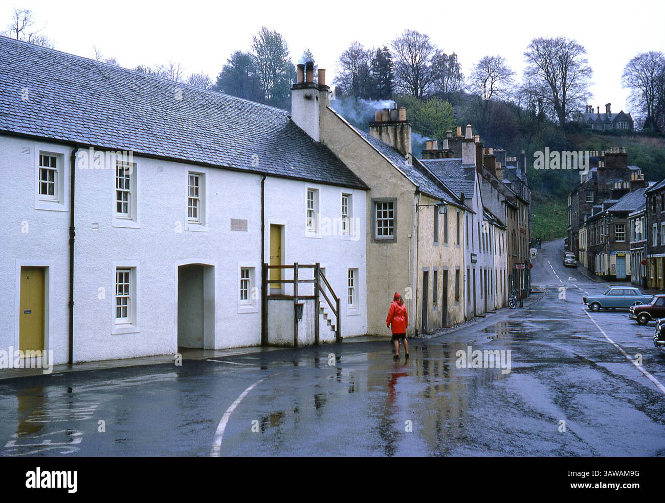 Woman walking through Dunkeld village, Perthshire, Scotland, on a rainy ...