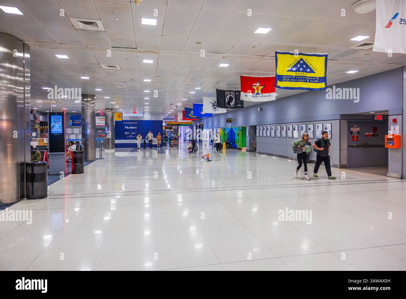 Interior view of JFK terminal with flags, passengers, memorial wall ...