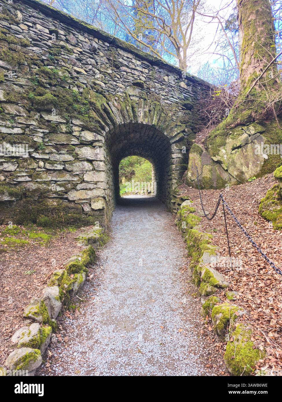A quiet tunnel carved through moss-covered rock in Ambleside, leading ...