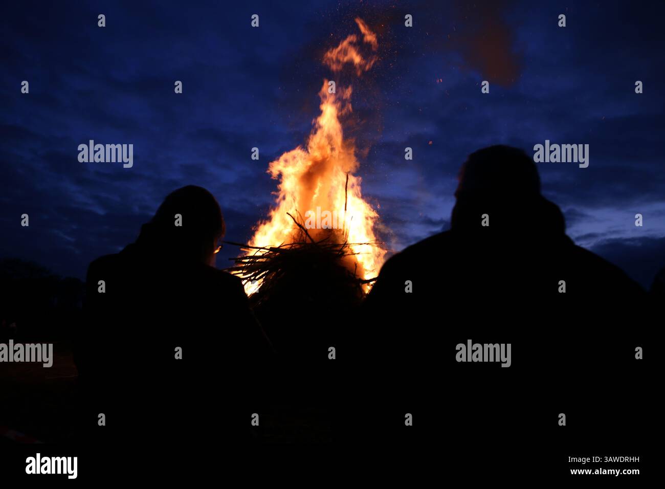 April 19, 2025, Cottbus, Brandenburg, Germany: Visitors look to the Easter fire at Branitzer ...