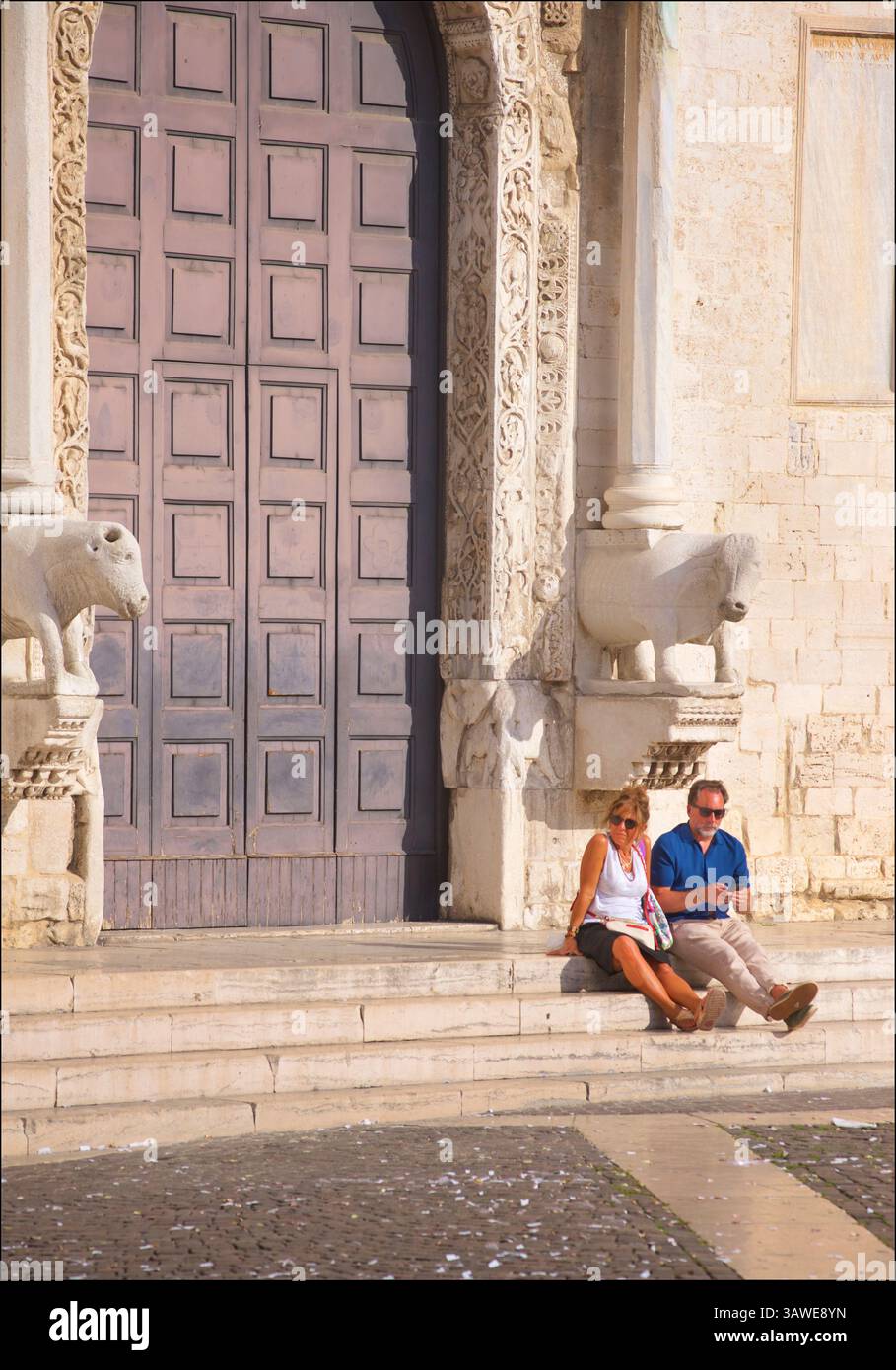 Tourist couple sitting on the steps outside the The Pontifical Basilica ...