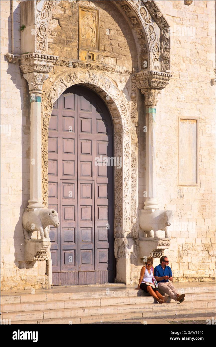 Tourist couple sitting on the steps outside the The Pontifical Basilica ...