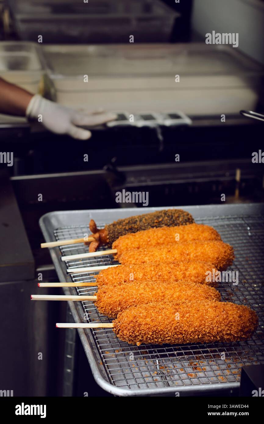A view of Korean style rice hot dogs resting on a rack and baking sheet ...