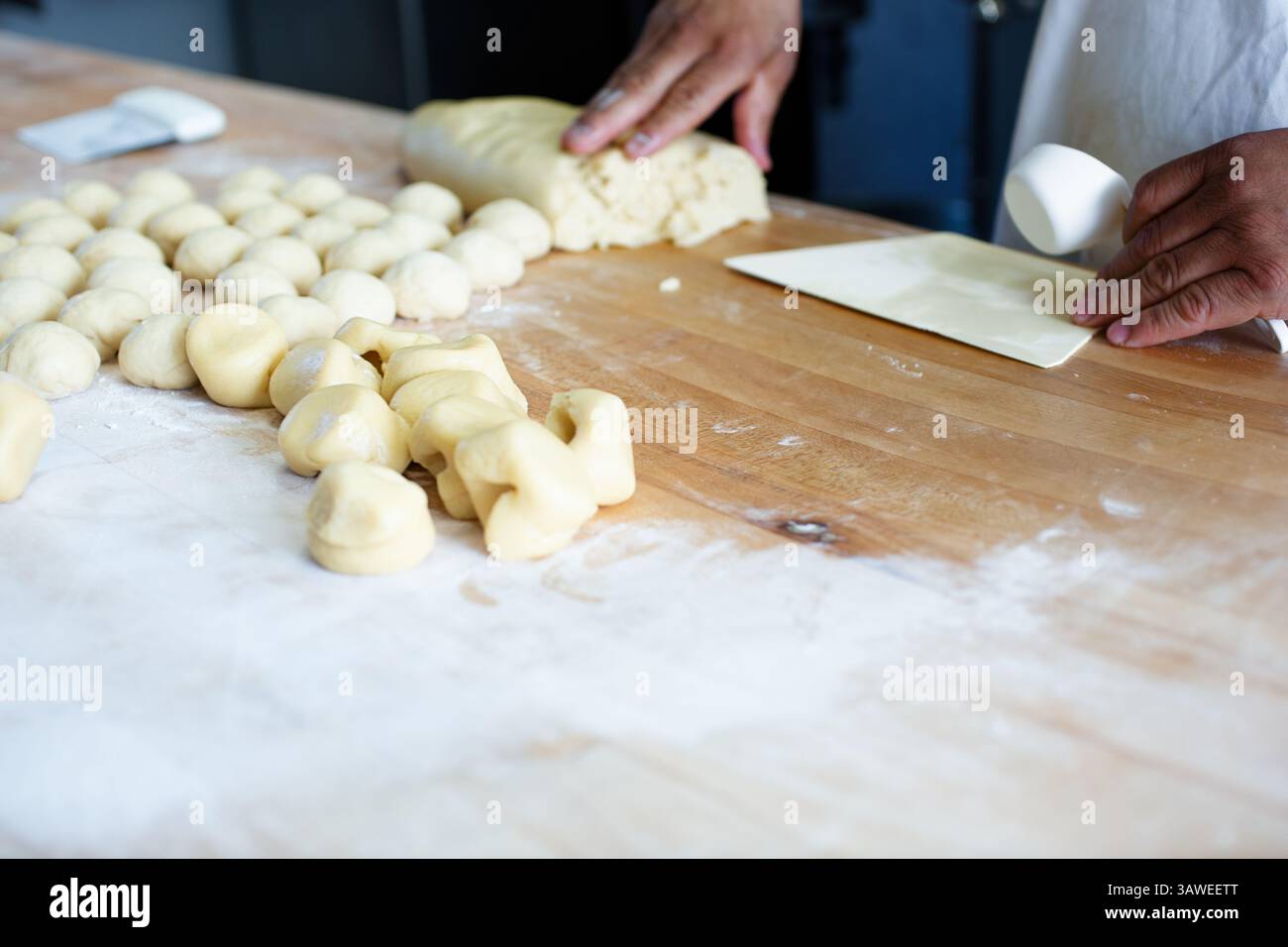 A view of a worker preparing bread dough balls in a restaurant kitchen ...