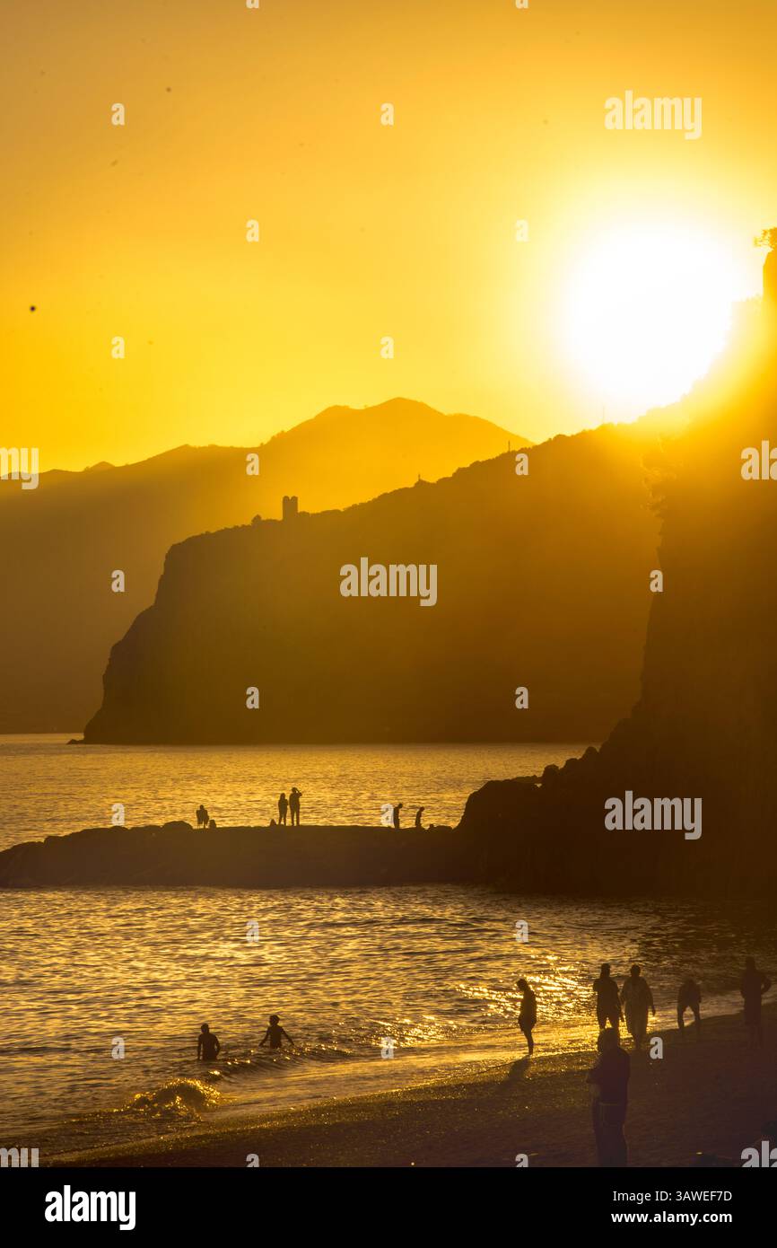 Silhouettes of beachgoers on Free Castelletto Beach at sunset. Spiaggia ...