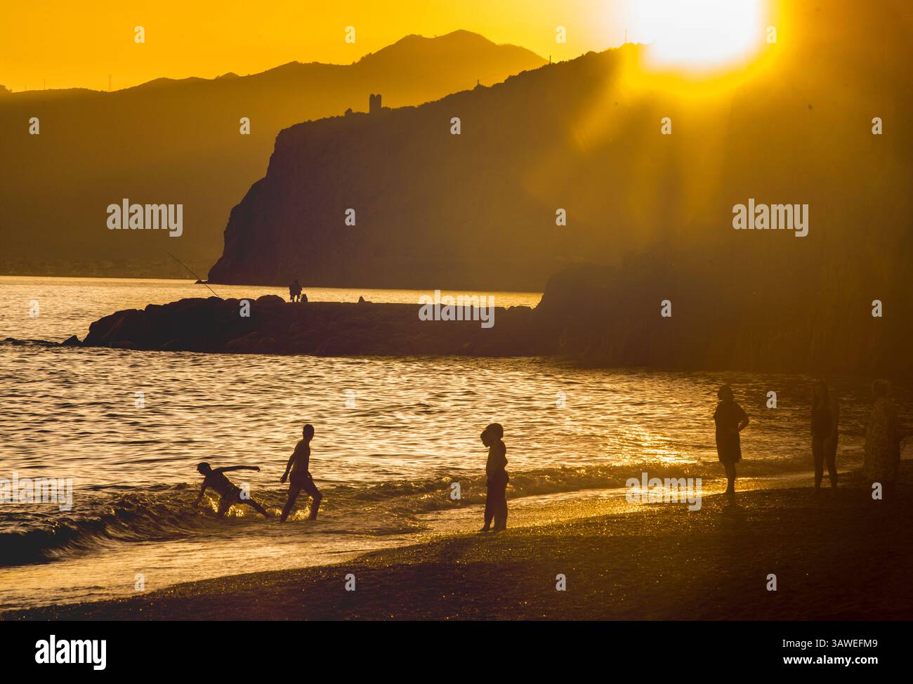 Silhouettes of beachgoers on Free Castelletto Beach at sunset. Spiaggia ...