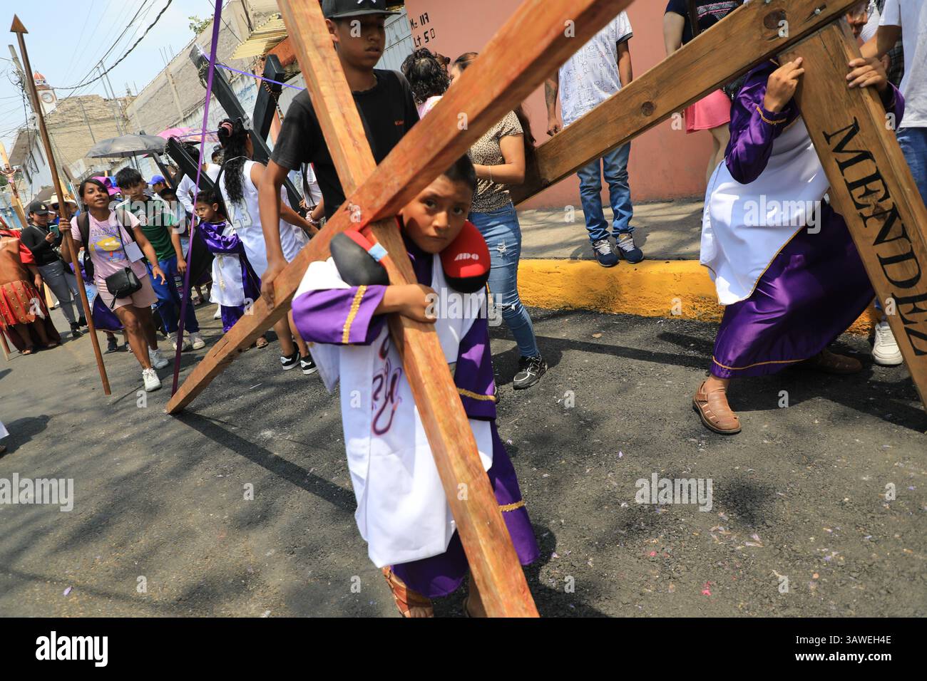 A child carries a cross while taking part during the passion of Christ ...