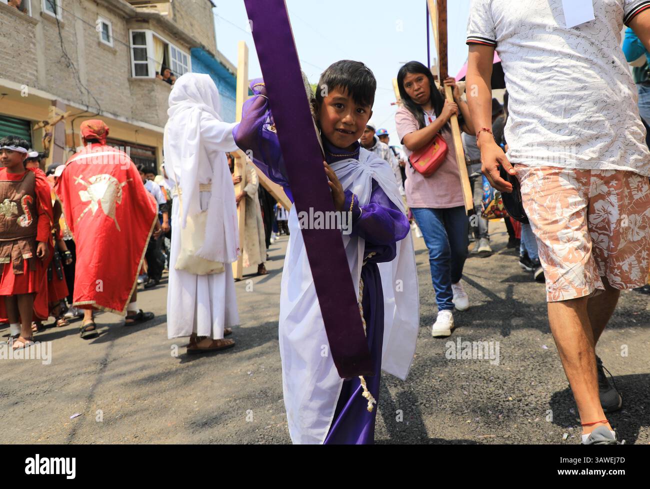A child carries a cross while taking part during the passion of Christ ...
