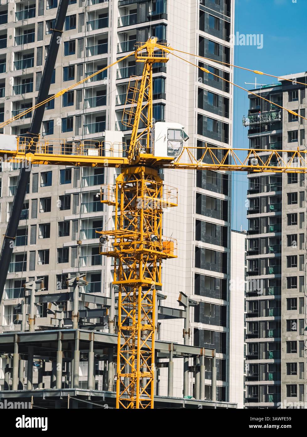 A tall yellow construction crane stands between modern high-rise ...