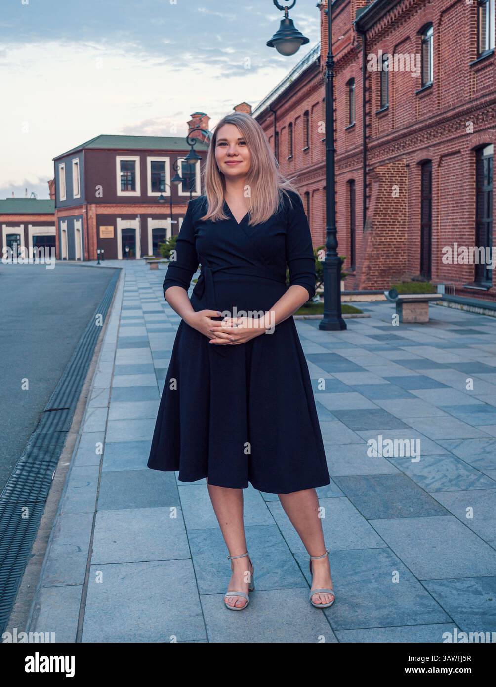 Elegant pregnant woman poses outdoors in a stylish black dress near ...