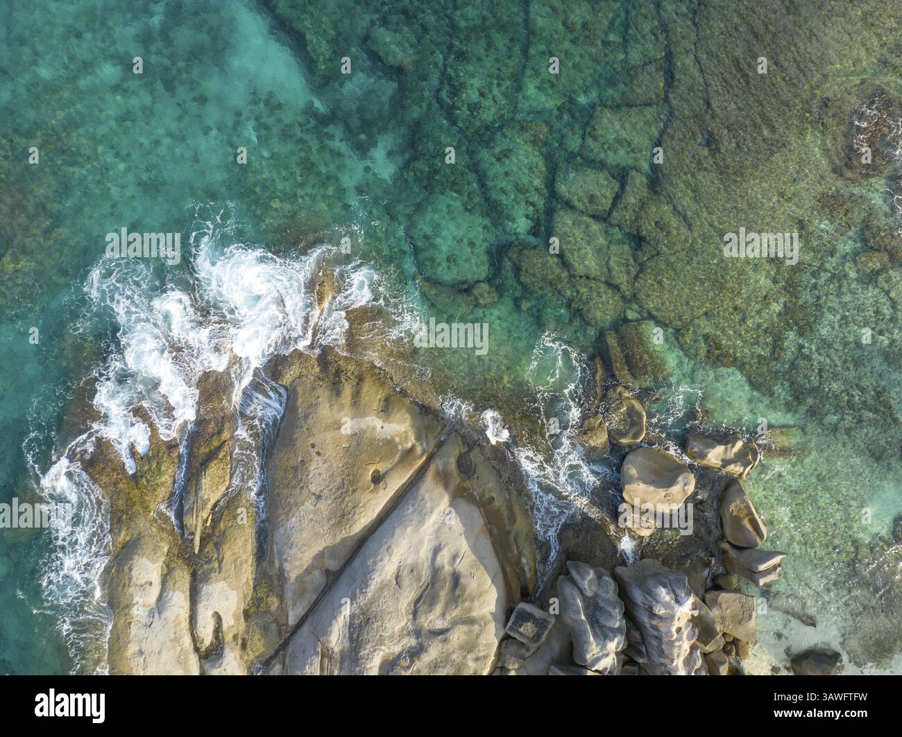 Aerial view of rocks in the sea with foaming waves in turquoise water ...