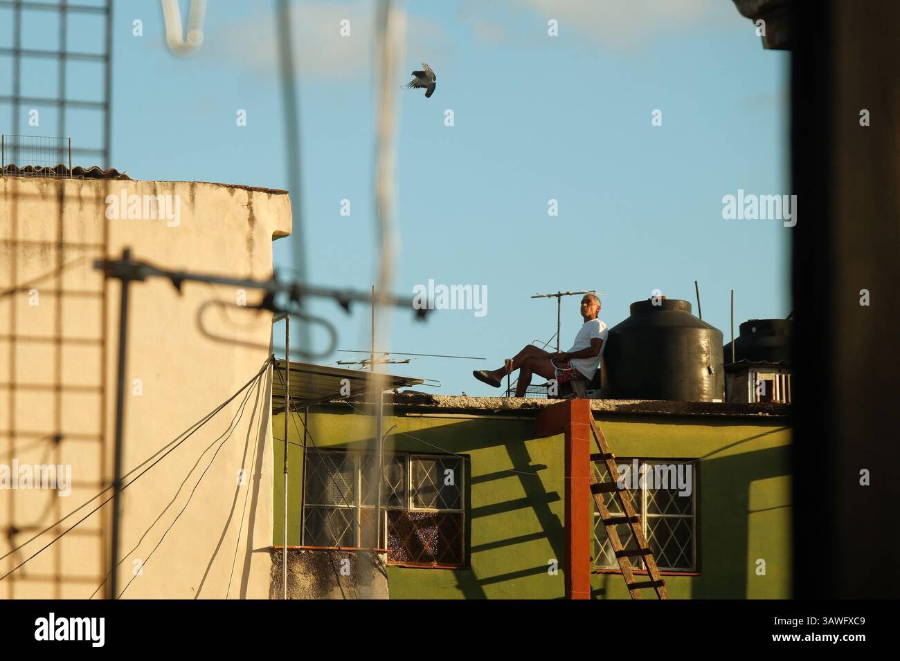 Havana, Cuba 2024 Apr15 - A local man relaxes on a rooftop in the ...