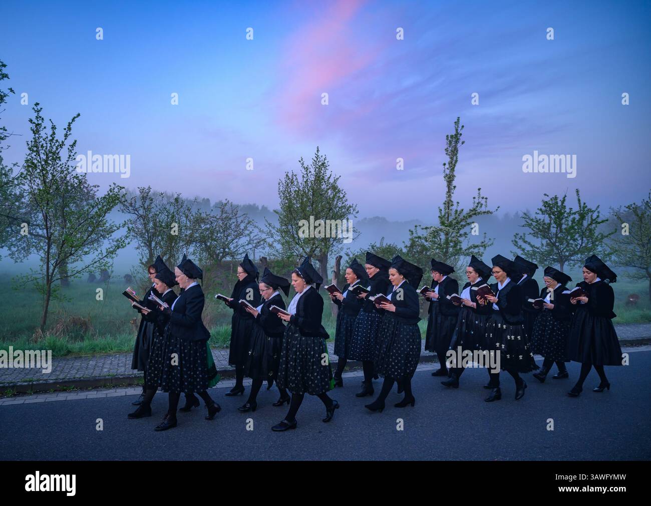20 April 2025, Brandenburg, Maust: Women in black church costumes sing ...