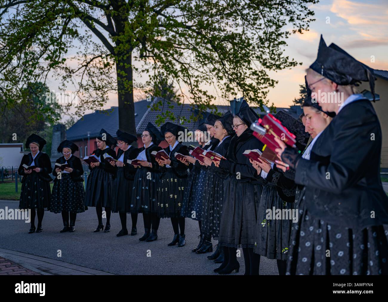 20 April 2025, Brandenburg, Maust: Women in black church costumes sing ...