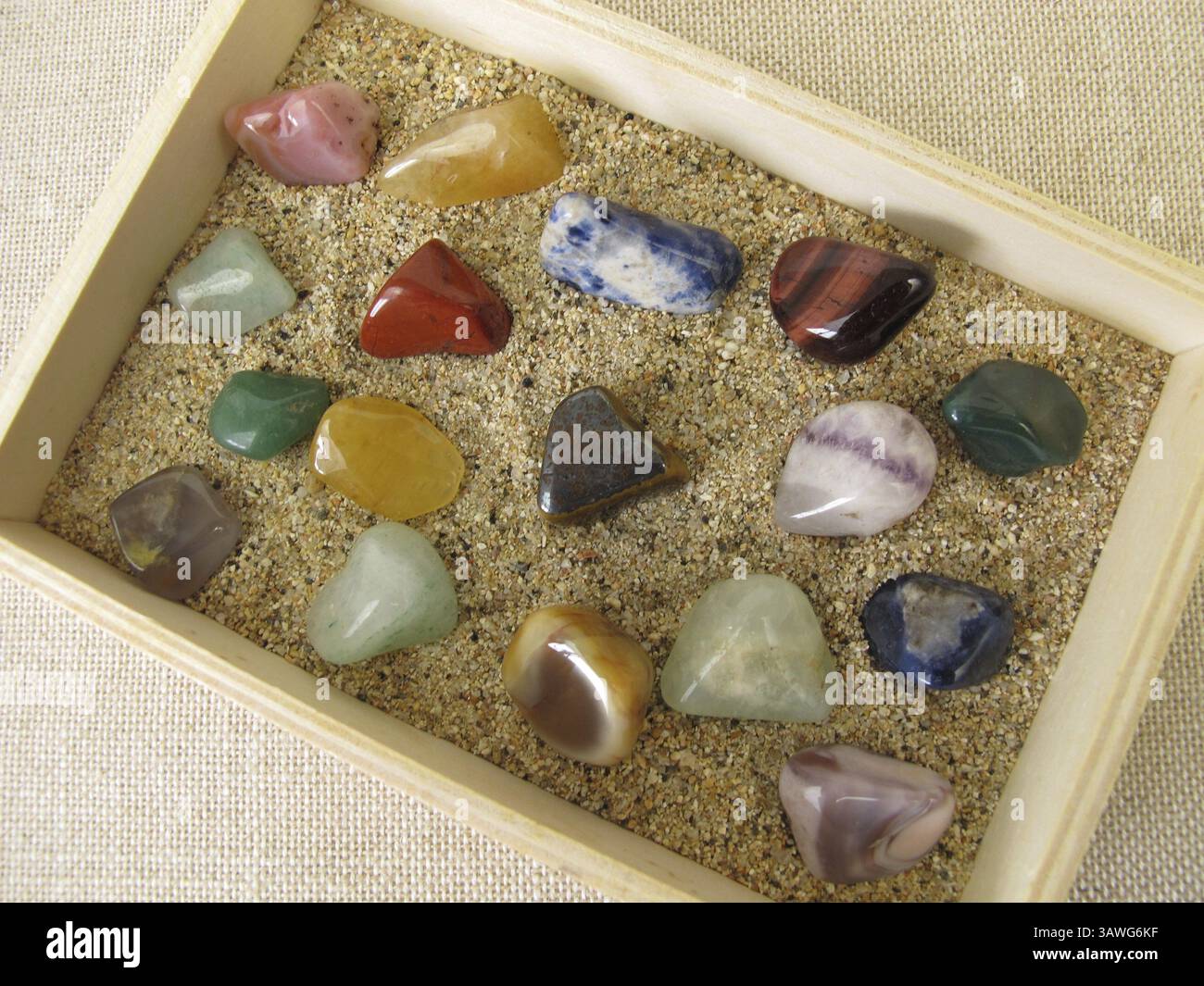 Cut coloured gemstones in a wooden box with sand Stock Photo - Alamy