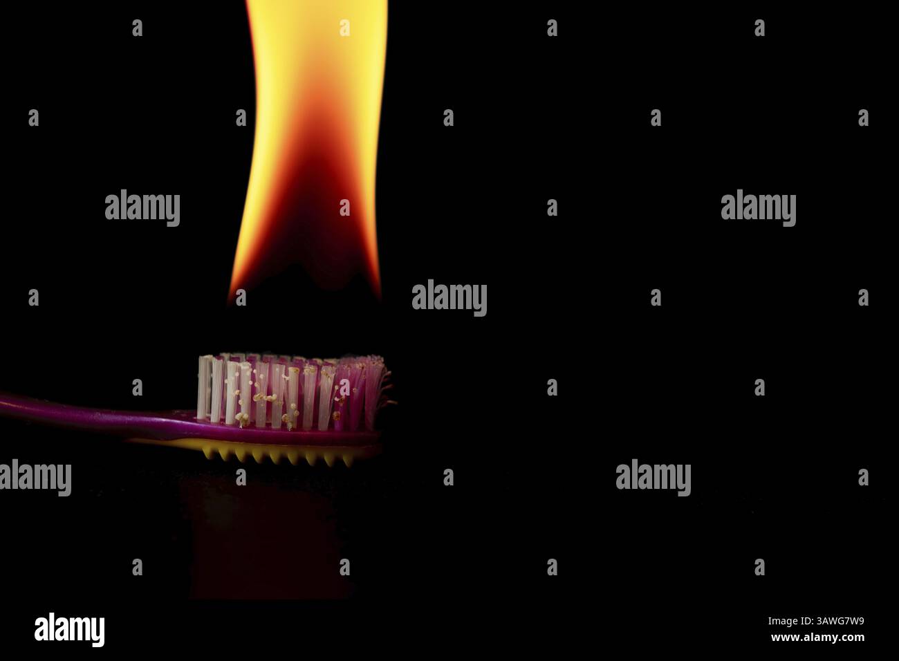 Toothbrush bristles burning on fire on a black background, representing ...